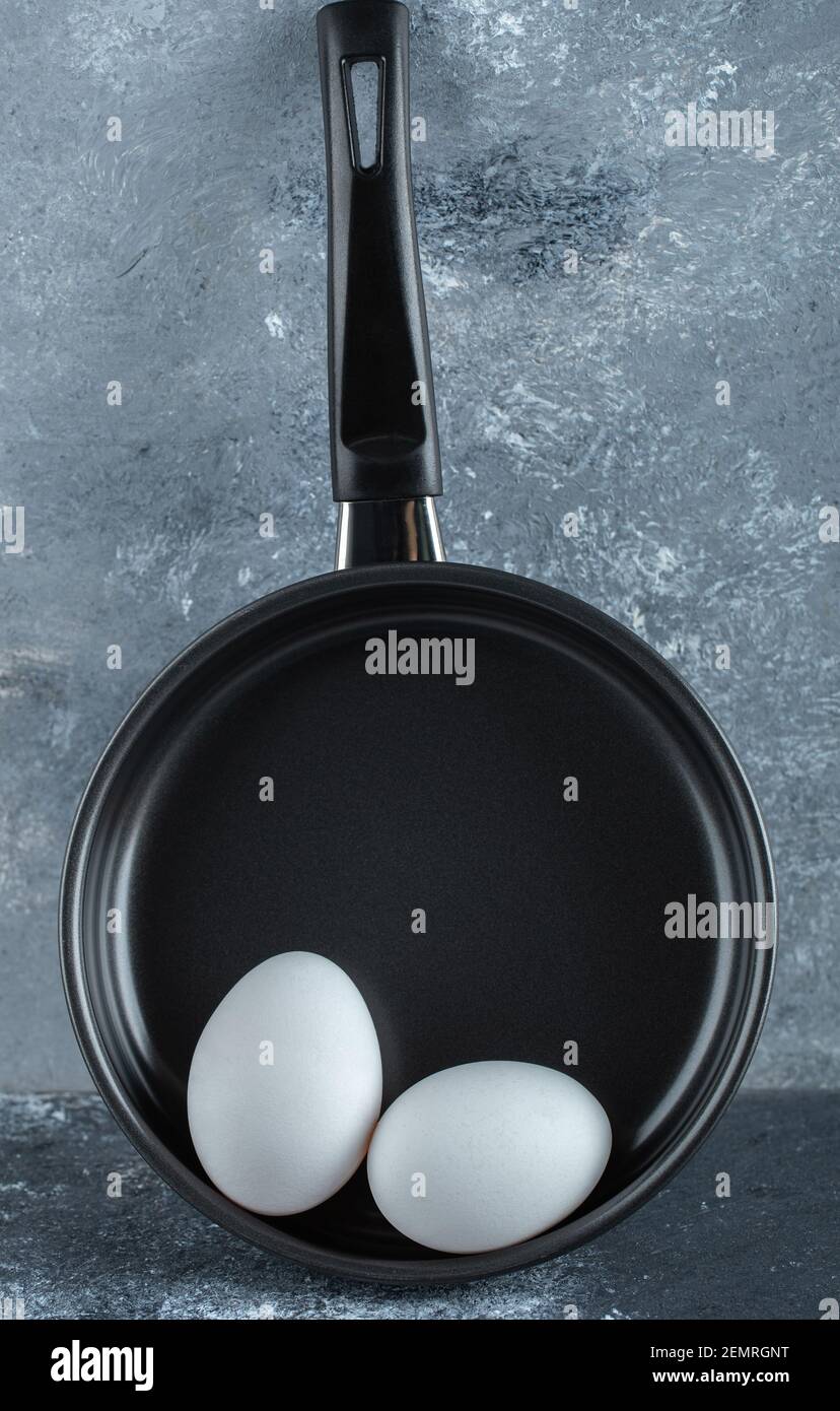 Vertical photo of two chicken egg and black frying pan Stock Photo - Alamy