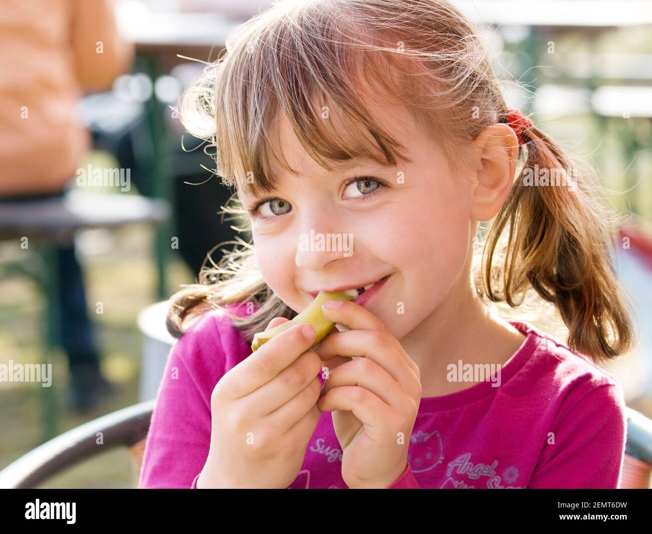 Satisfied little girl eating pickle Stock Photo - Alamy