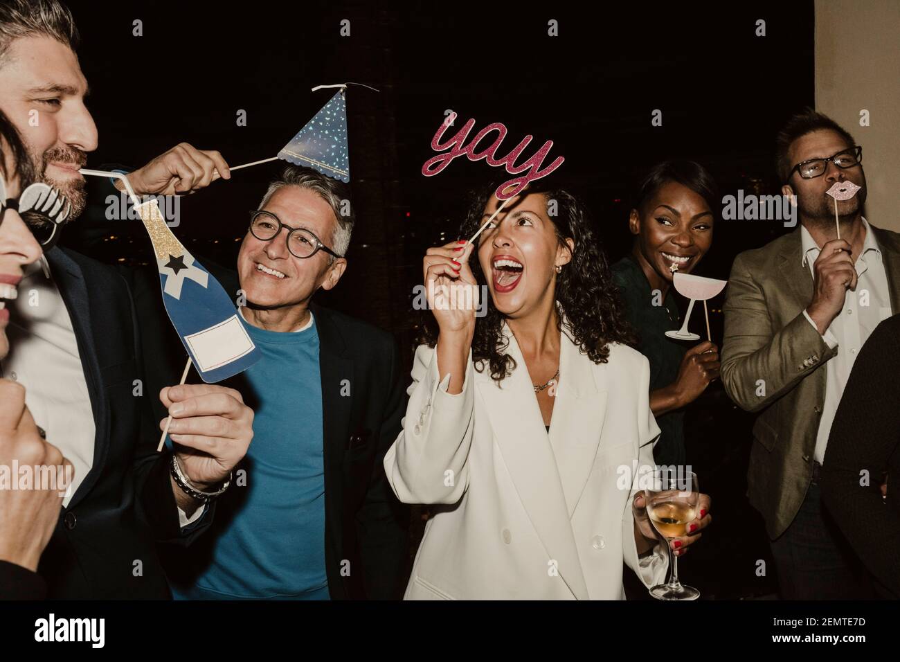 Cheerful business people enjoying with props during company party at ...