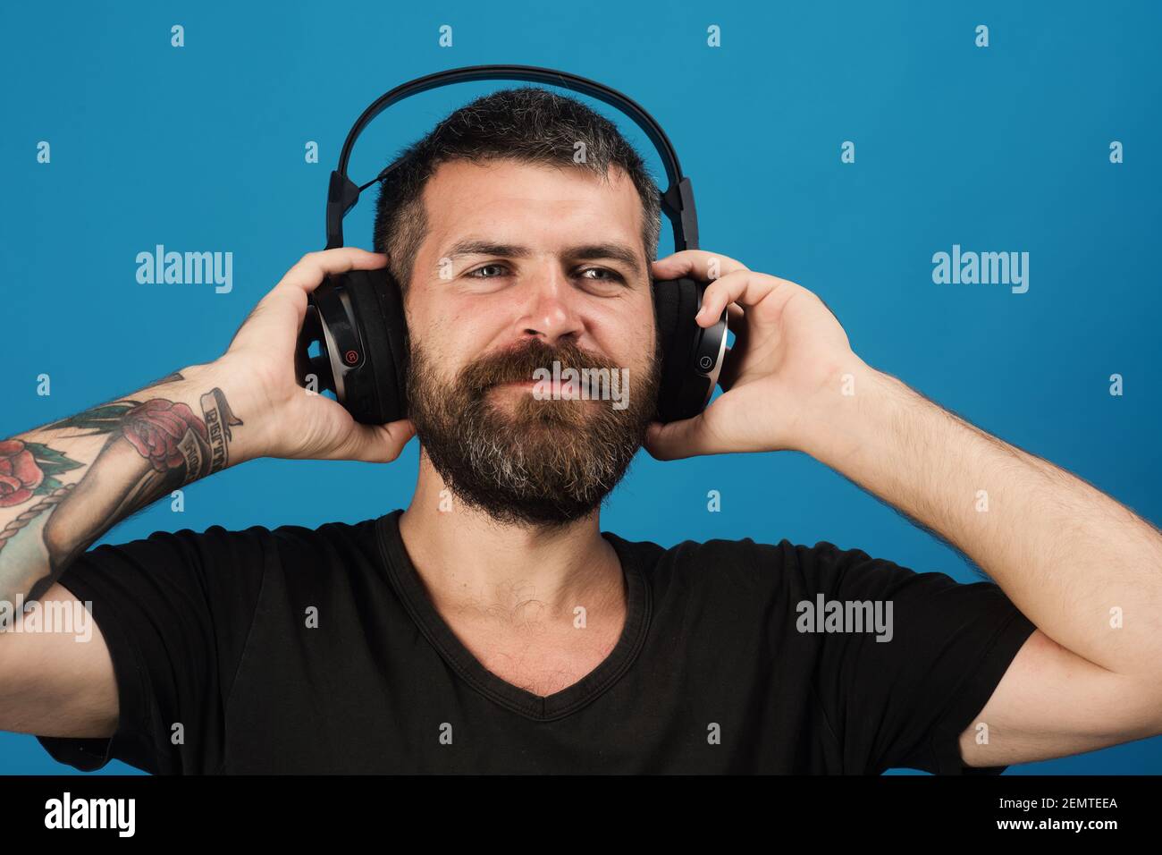 Singer with beard and smiling face enjoys music. Man holds headphones ...