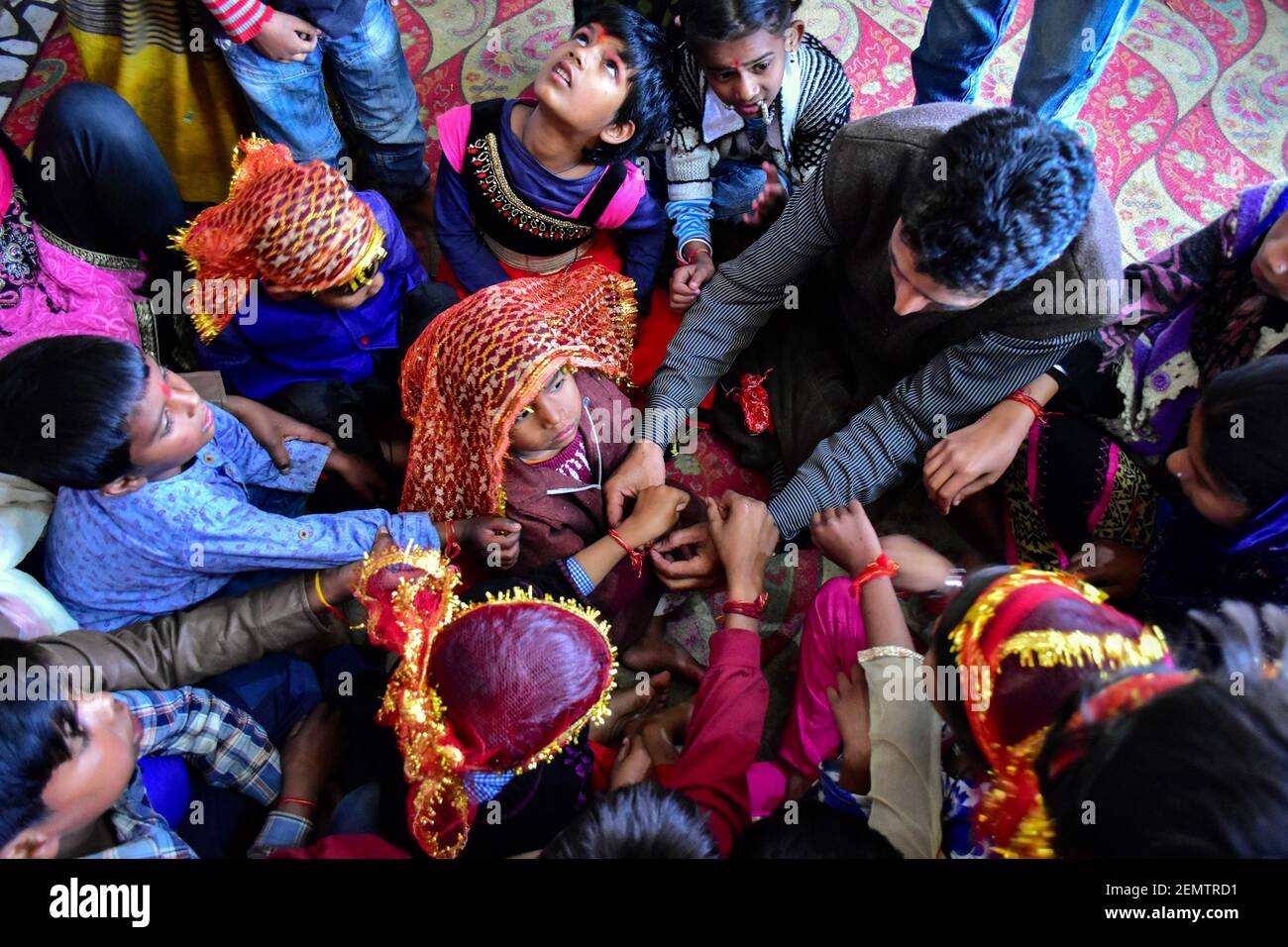 A priest seen tying sacred threads on the arms of young devotees at a ...