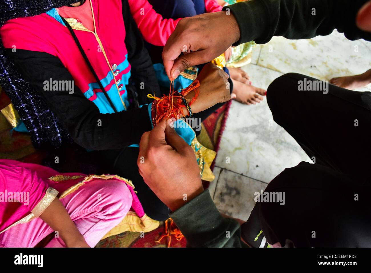 A priest seen tying a sacred thread on the arm of a devotee at a temple ...