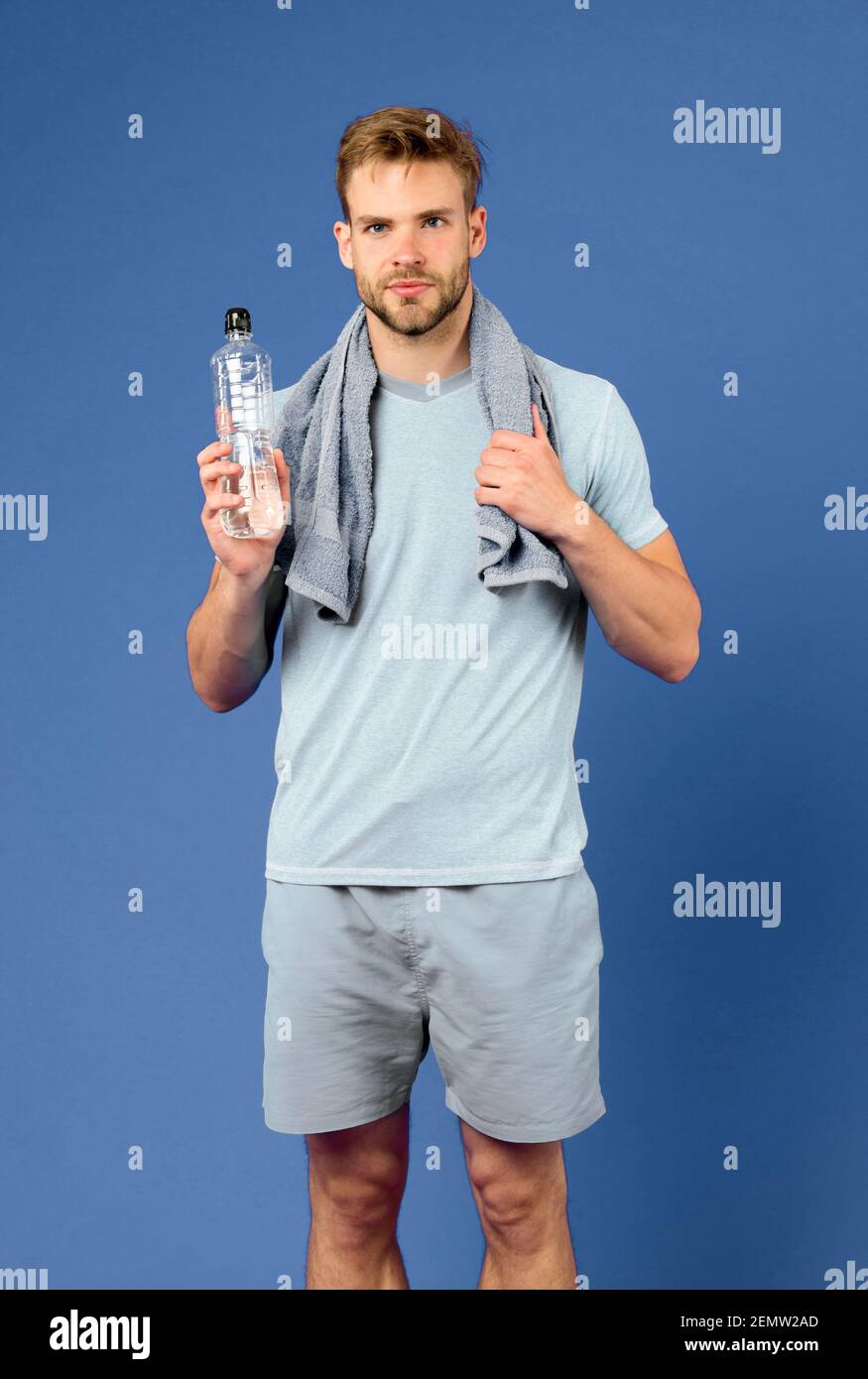Stay hydrated. Man with towel on shoulders hold bottle. Athlete drink ...
