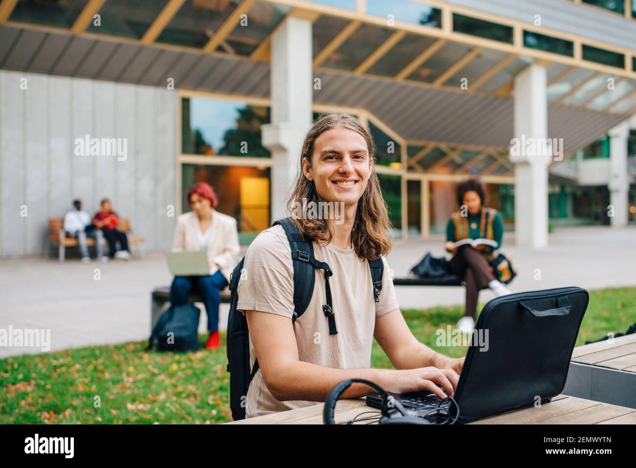 Portrait of male students e-learning through laptop in university ...