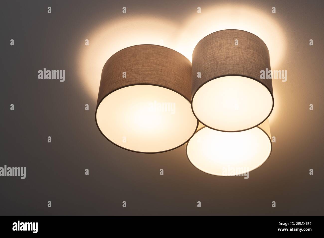 A modern trendy ceiling lamp composed of a group of three cylinders, it ...