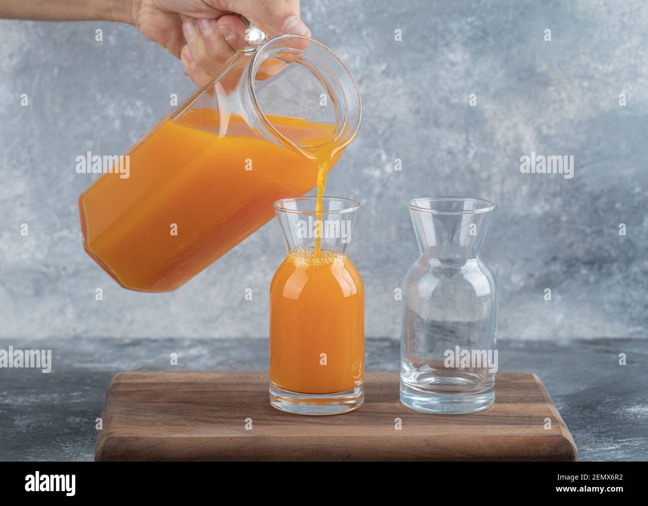 Man hand pouring orange juice into glass on marble background Stock ...