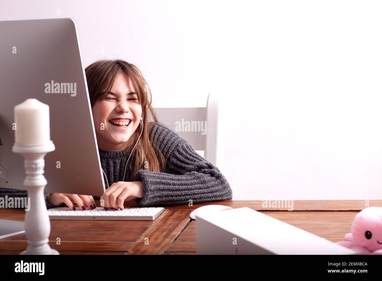 Little girl sitting on a chair with a computer in front of her and ...