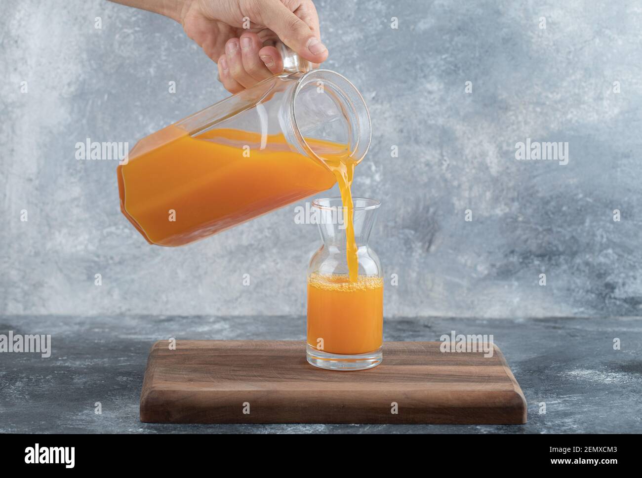 Male hand pouring orange juice into glass Stock Photo - Alamy