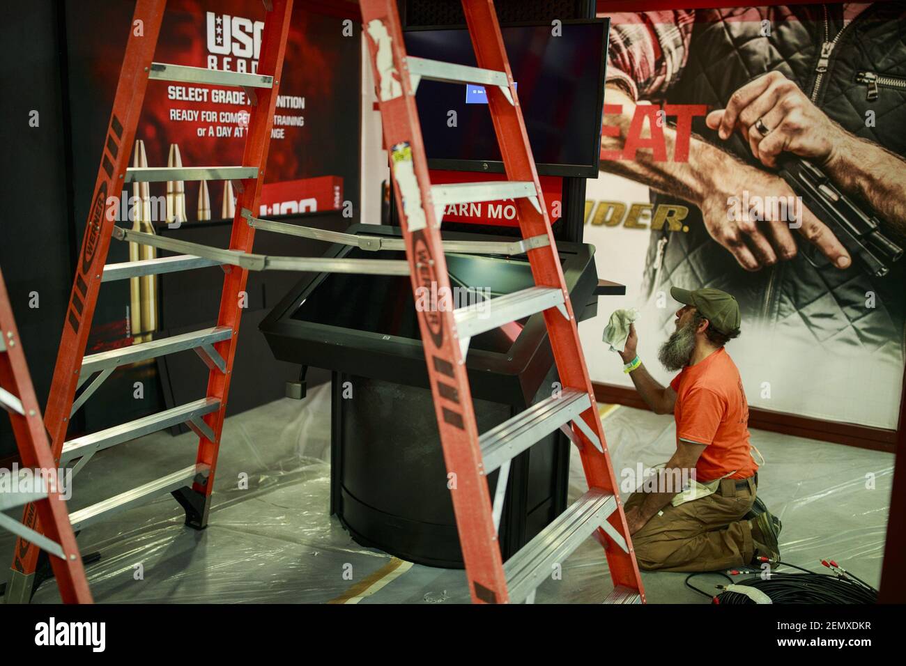 A worker sets up the Winchester Gear booth. Vendors prepare booths in ...
