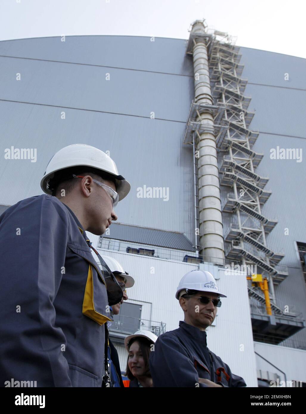Workers are seen walking in front of the New Safe Confinement covering ...