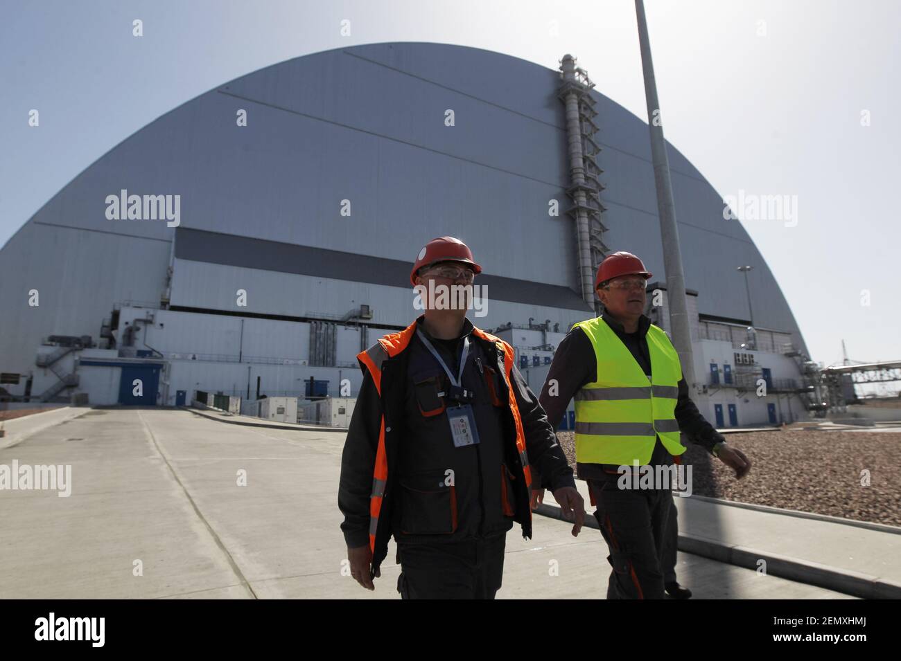 Workers are seen walking in front of the New Safe Confinement covering ...