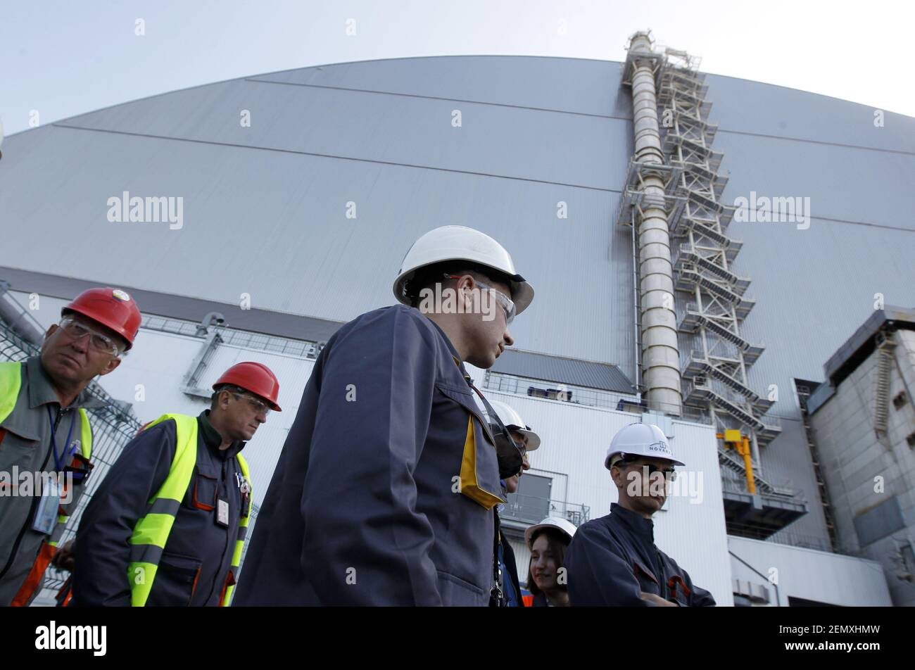 Workers are seen walking in front of the New Safe Confinement covering ...