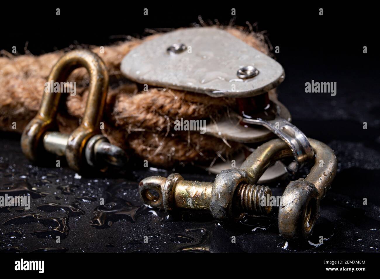 Wet shackles and heavy jute rope wrapped on rollers in a sailing pulley ...