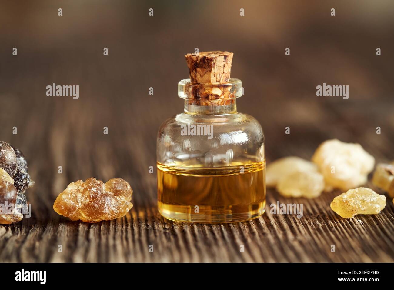 A bottle of essential oil with frankincense resin on wooden background ...
