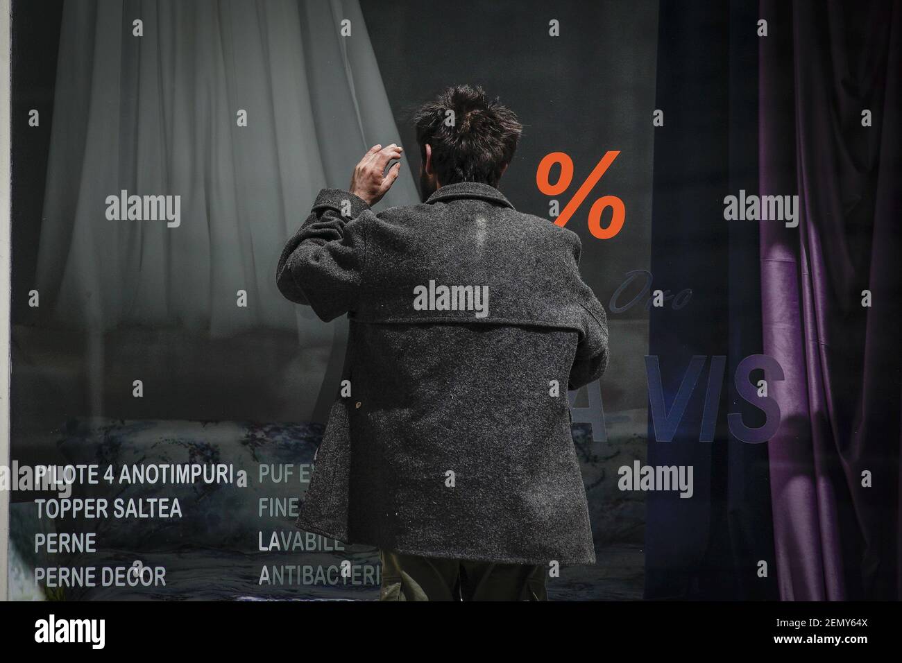 A homeless man looks at a shop window display in Bucharest, Romania on ...