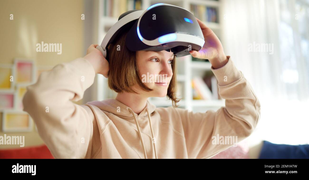 Pretty teenage girl wearing virtual reality headset at home. Cute teen ...