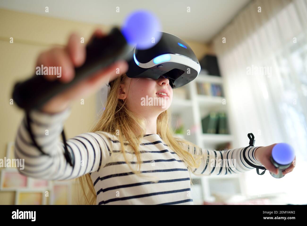 Pretty young girl wearing virtual reality headset at home. Cute kid ...