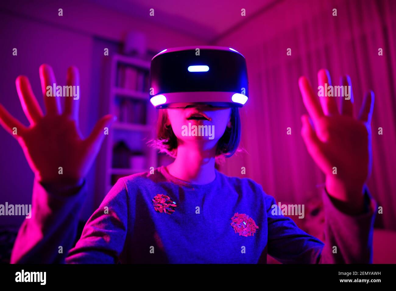 Pretty teenage girl wearing virtual reality headset in a dark room ...