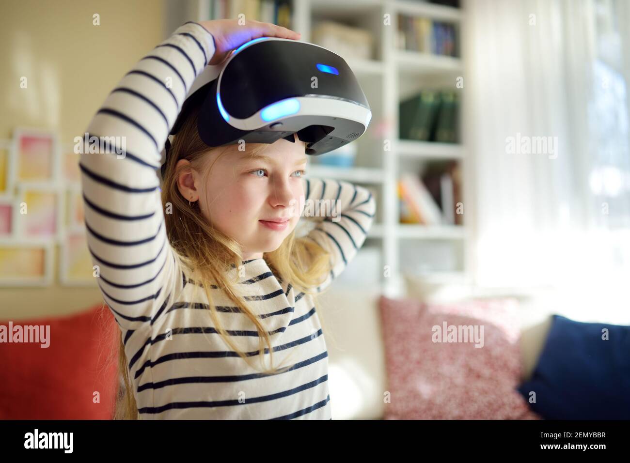 Pretty young girl wearing virtual reality headset at home. Cute kid ...
