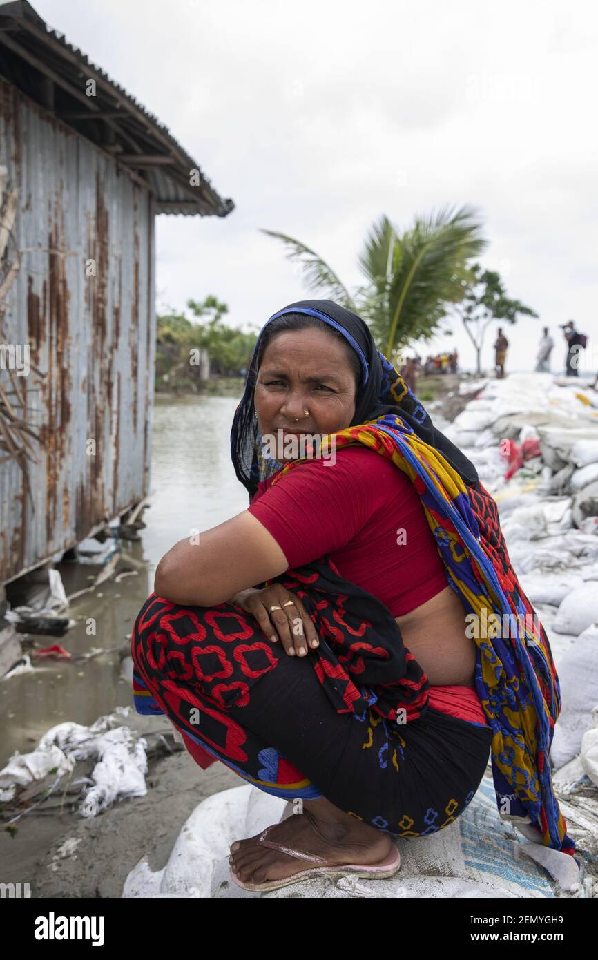 Bangladeshi woman Rubi Begum (40) sits on sandbag embankment that was ...