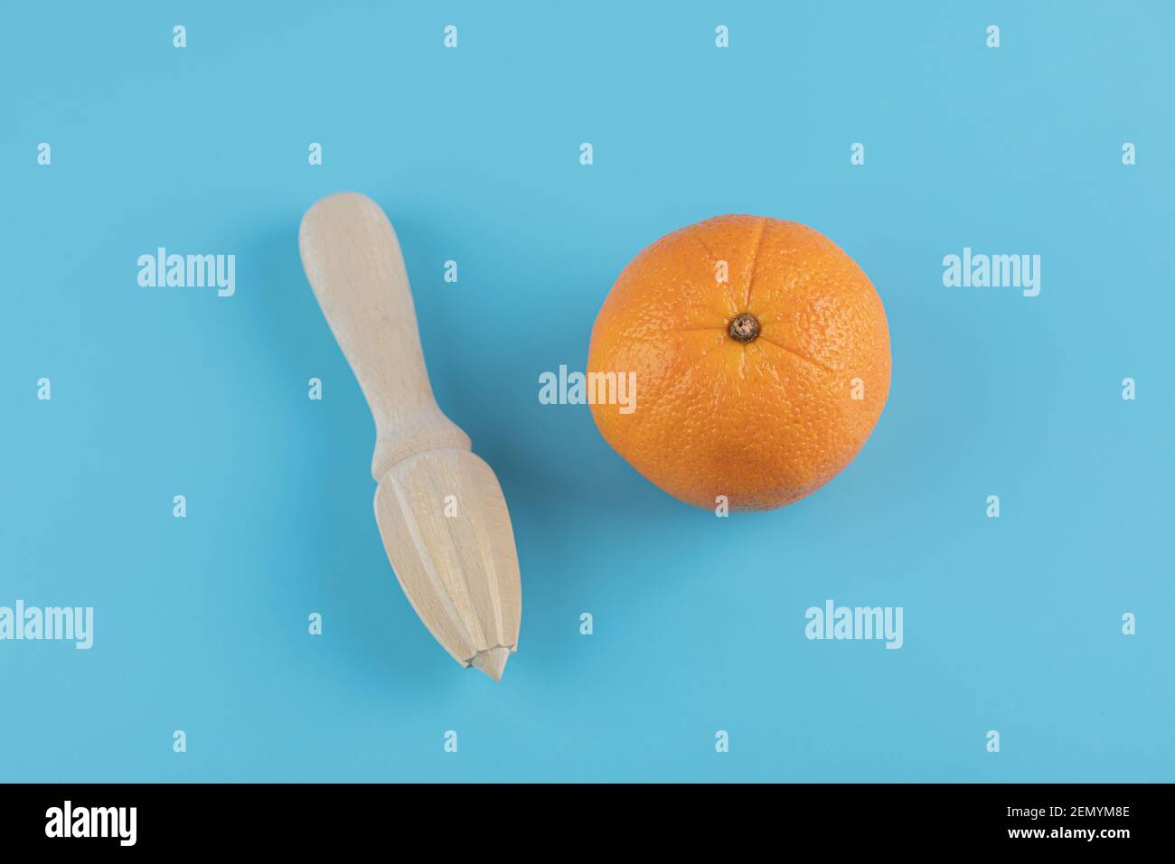 Orange and wooden reamer on blue background Stock Photo - Alamy