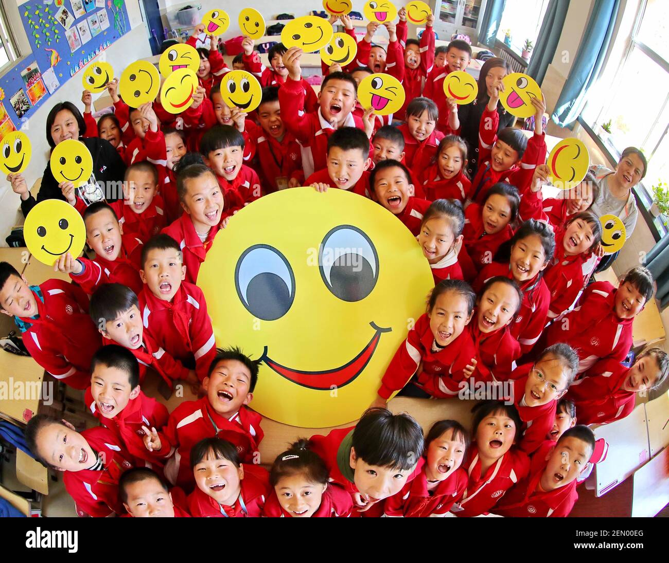 Smiley young Chinese students show smiling cartoon faces they made to ...