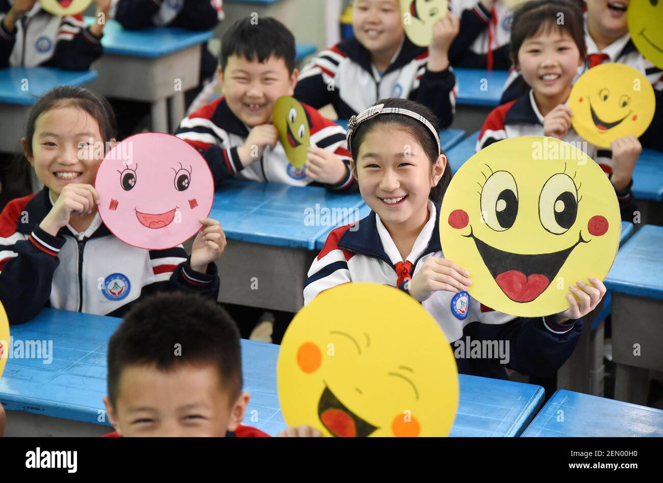 Smiley young Chinese students show smiling cartoon faces they made to ...