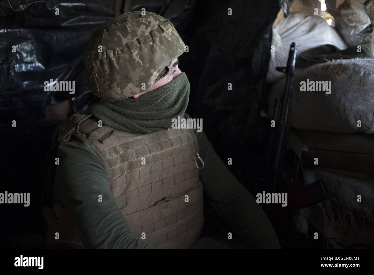 A Ukrainian soldier sits in an observation tower next to an AK-74 rifle ...