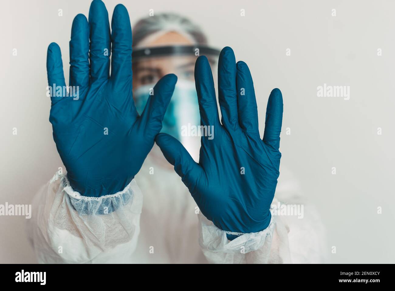 Healthcare worker with shield and mask showing stop gesture Stock Photo ...