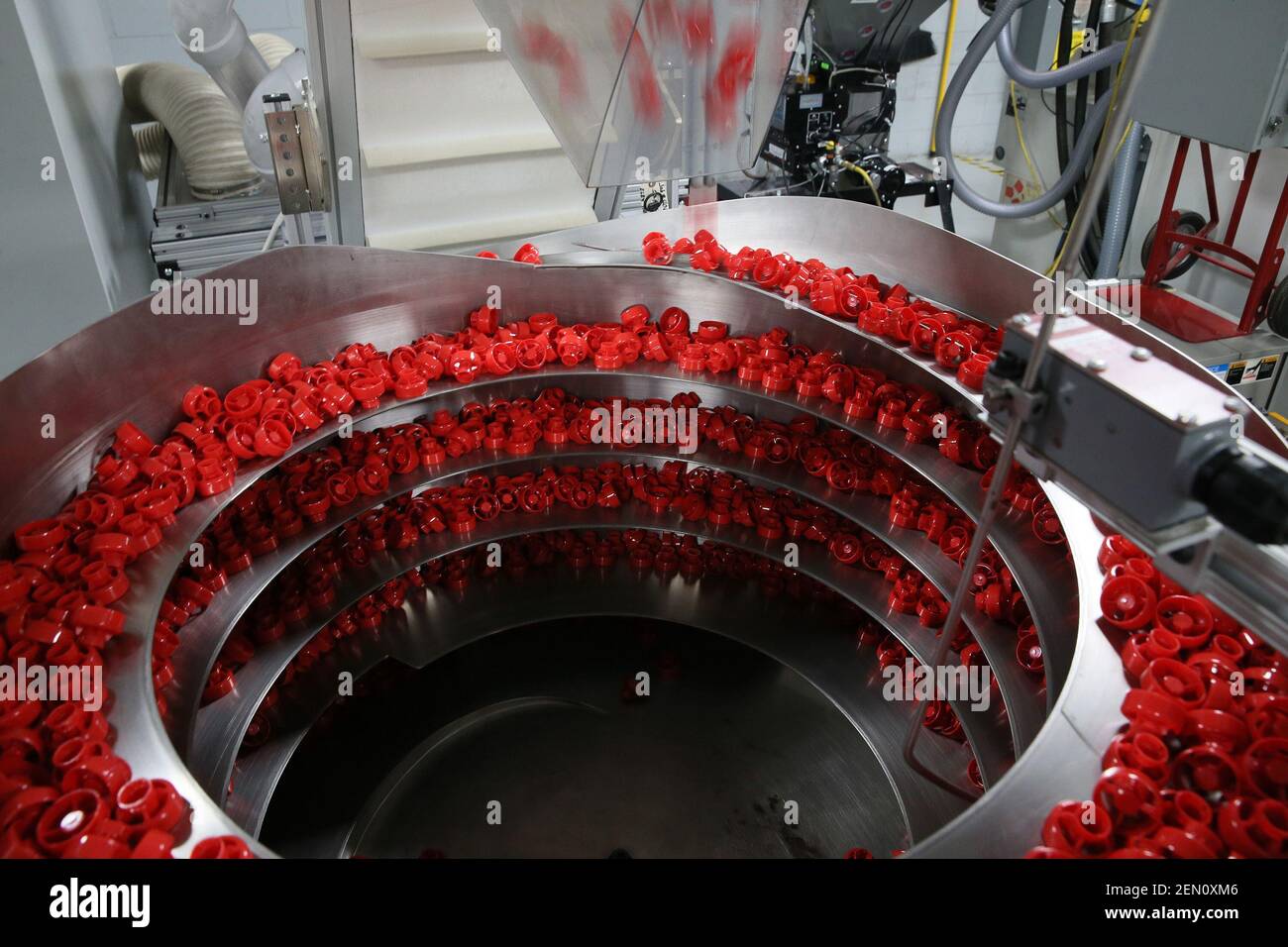 Plastic caps for squeezable pouches swirl around in a machine at Hoffer ...