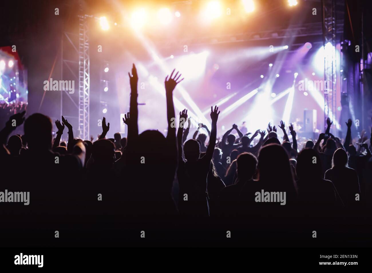 Rock concert, cheering crowd in front of bright colorful stage lights ...