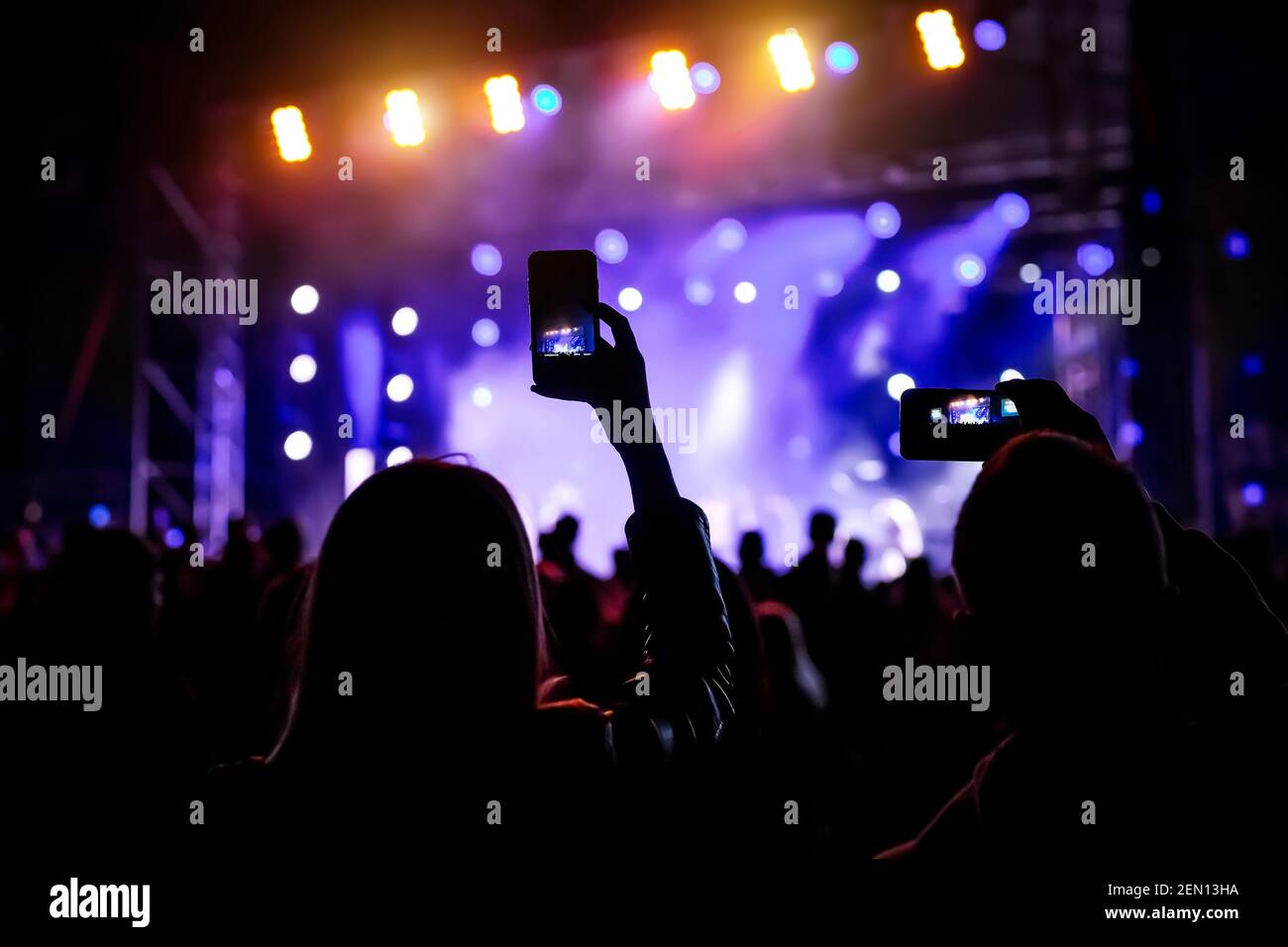 Taking a photo by mobile phone at a concert in front of the stage light ...