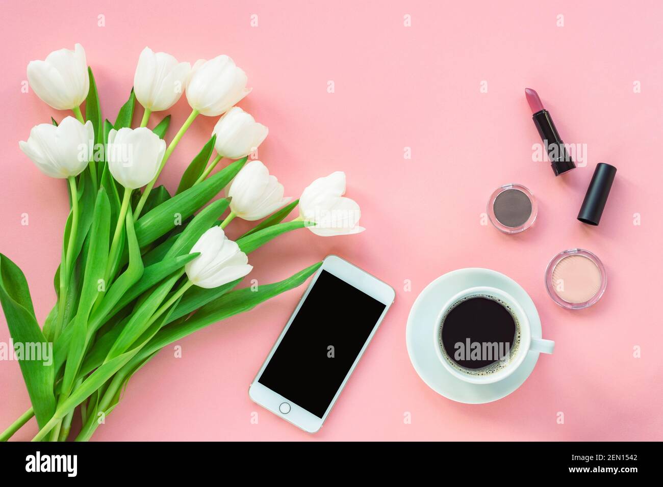 Cup of coffee, phone, make up tools, cosmetics and bouquet of tulips on ...
