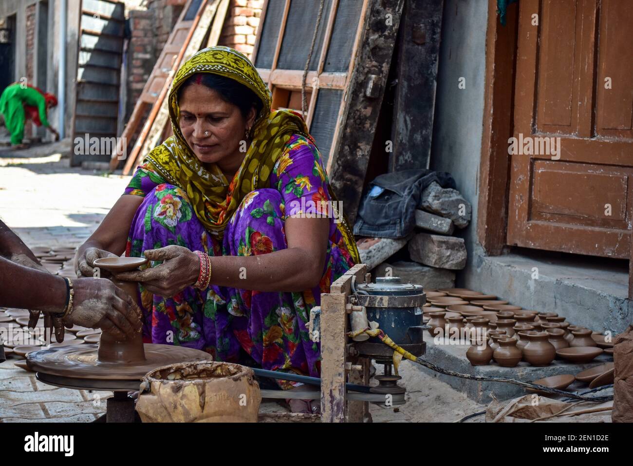 An Indian woman potter seen making traditional earthen lamps and pots ...