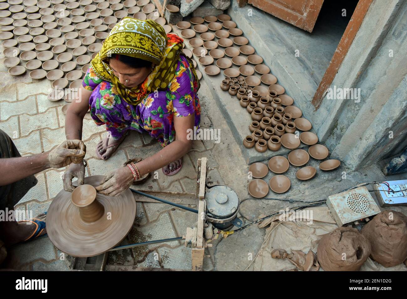 An Indian woman potter seen making traditional earthen lamps and pots ...
