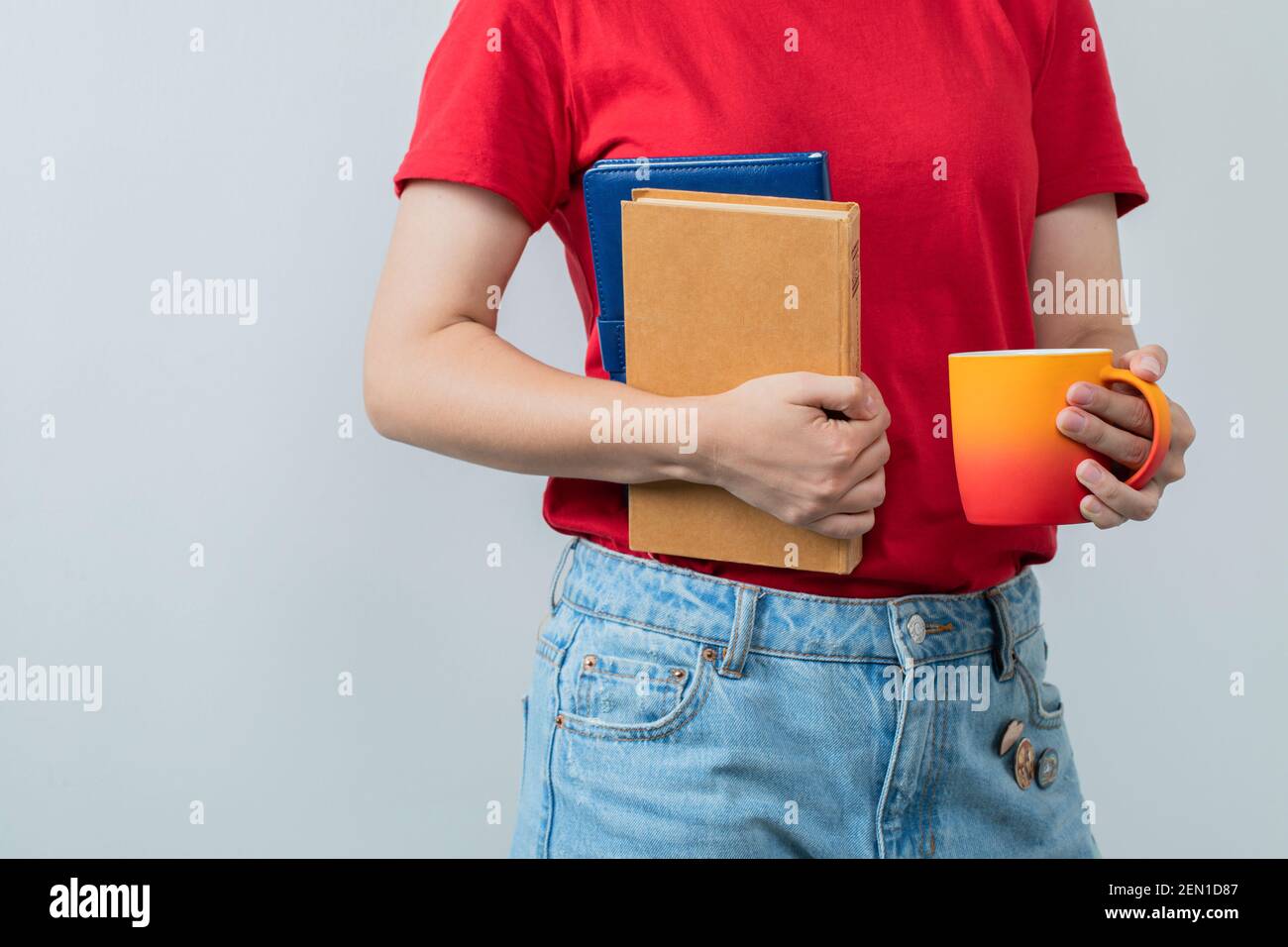 Female model in red shirt holding books and a cup of drink Stock Photo ...