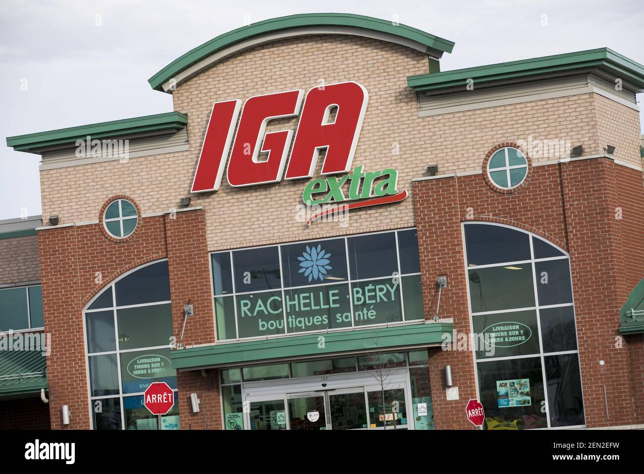 A logo sign outside of a IGA retail grocery store location in ...