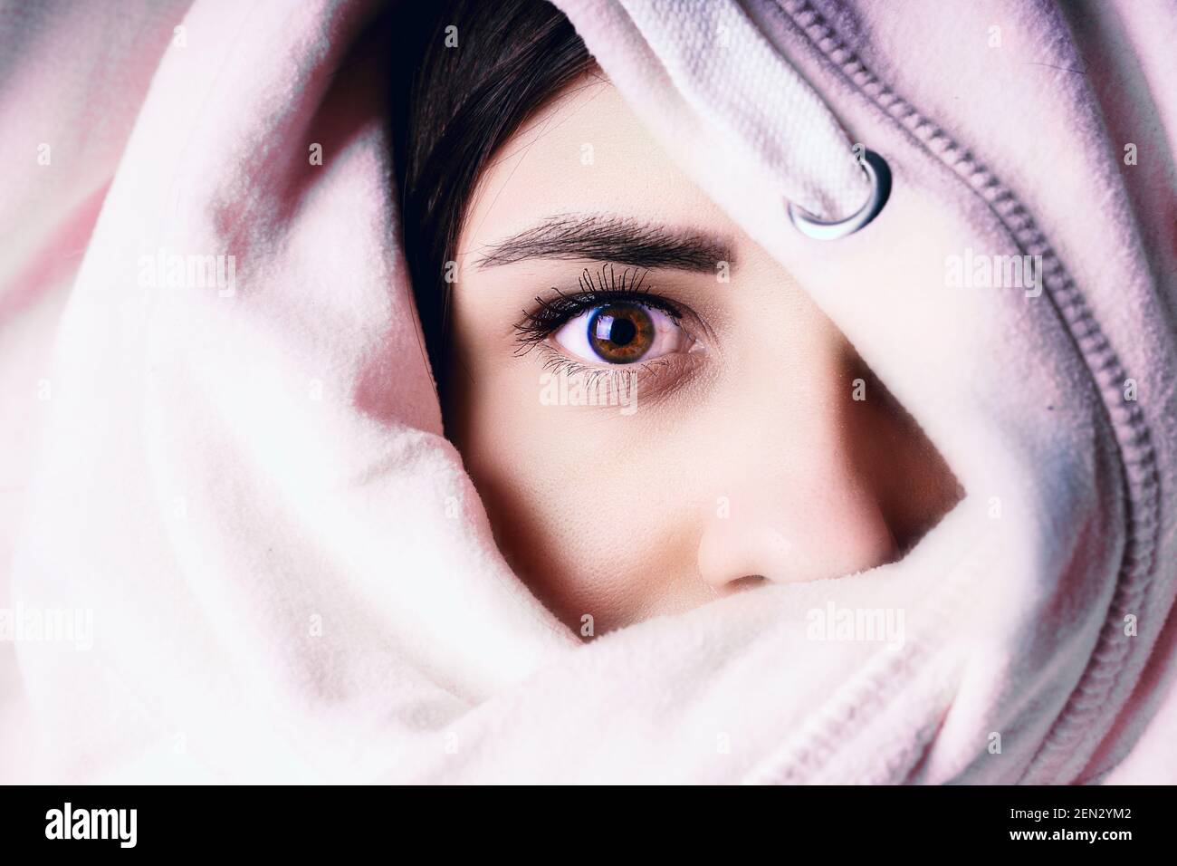 The woman hides her face behind the hood. Stylish female posing in a ...