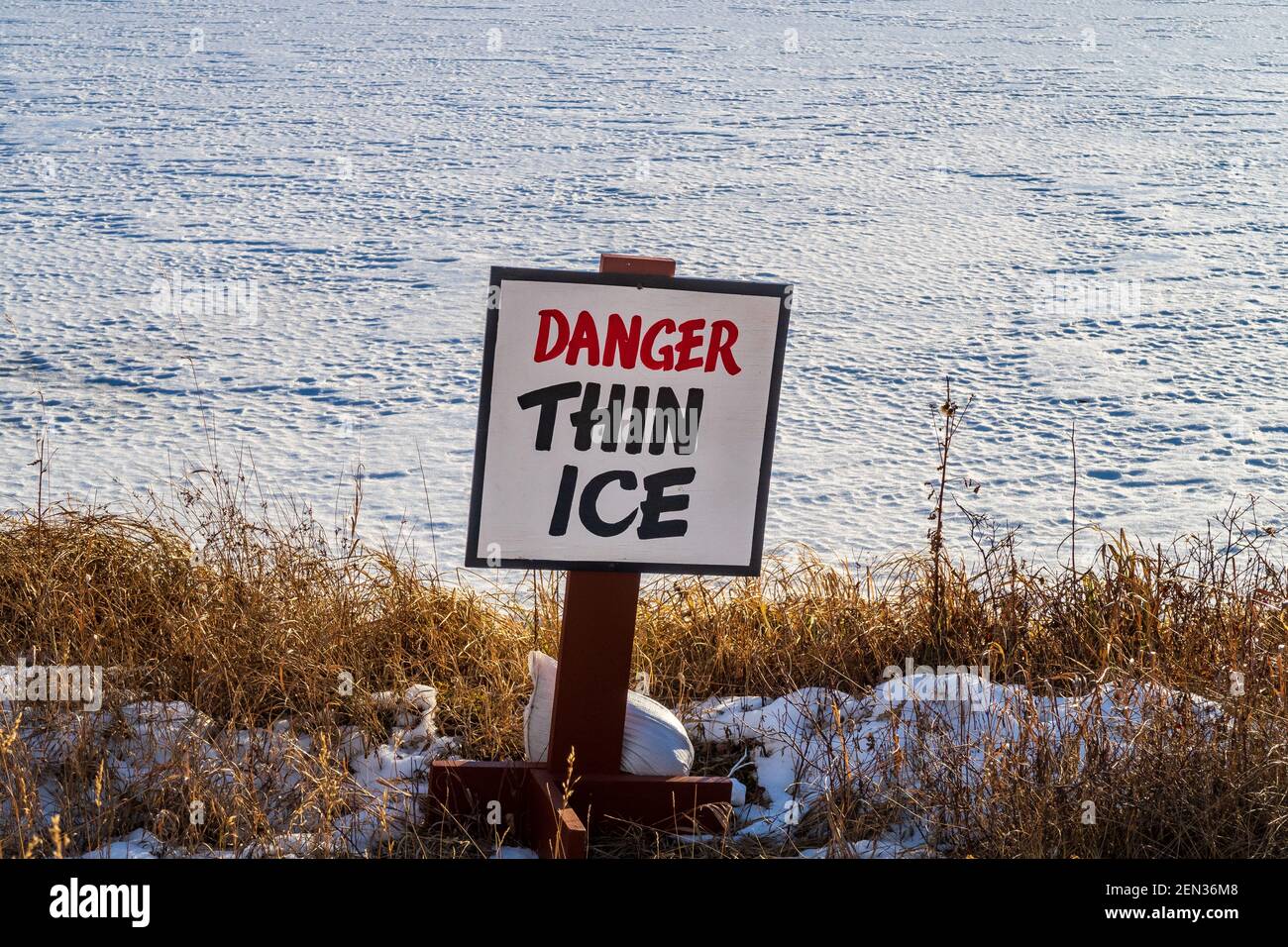 Warning sign "Danger thin ice" in front of a frozen lake in Canada ...