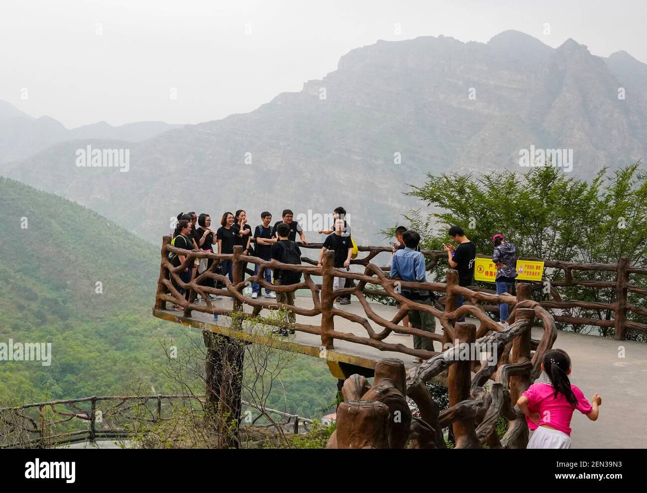 Tourists walk on a zigzag cliff road around a mountain at the Shidu ...