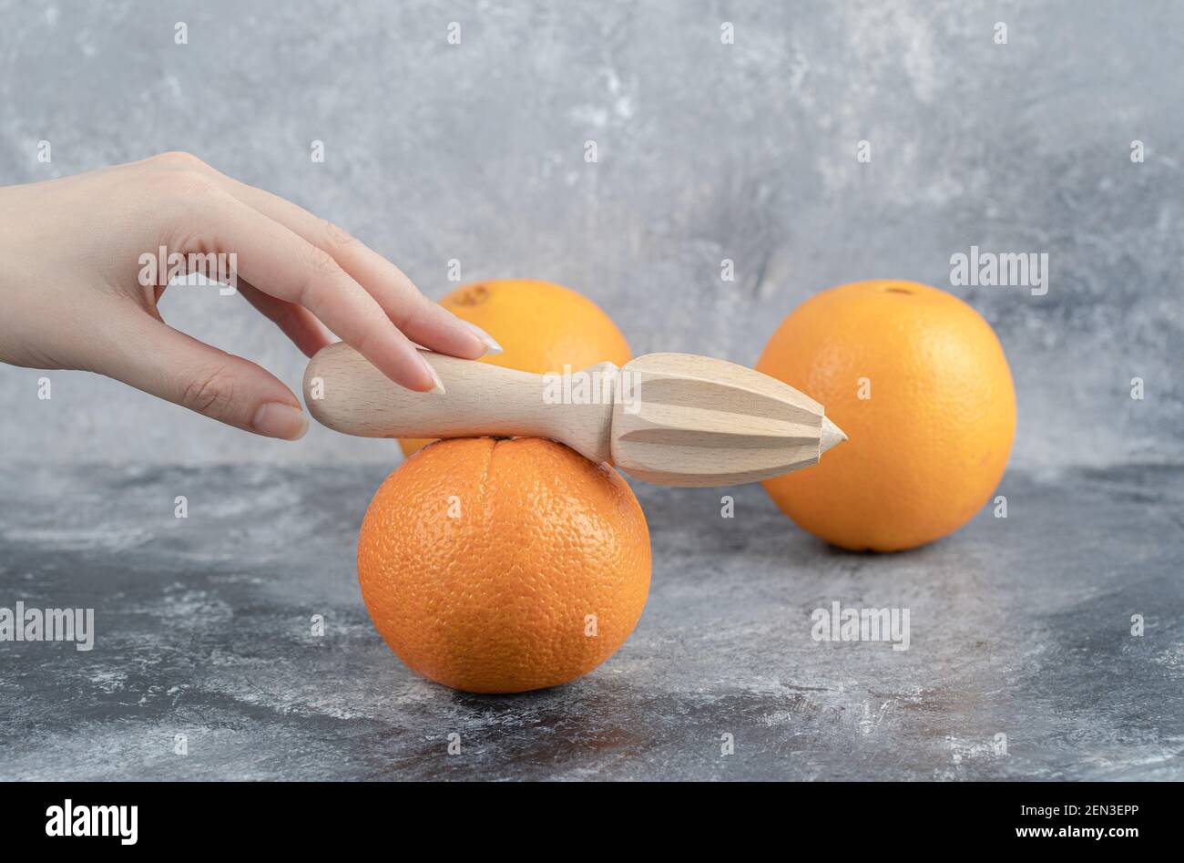 Female hand holding wooden squeezing tool on marble background Stock ...