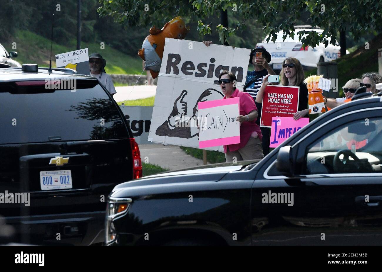 Protesters hold placards as US President Donald Trump's motorcade ...