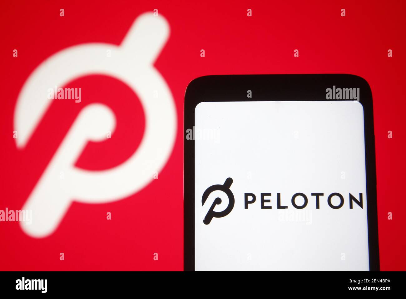 In this photo illustration a Peloton logo is seen on a smartphone and a ...