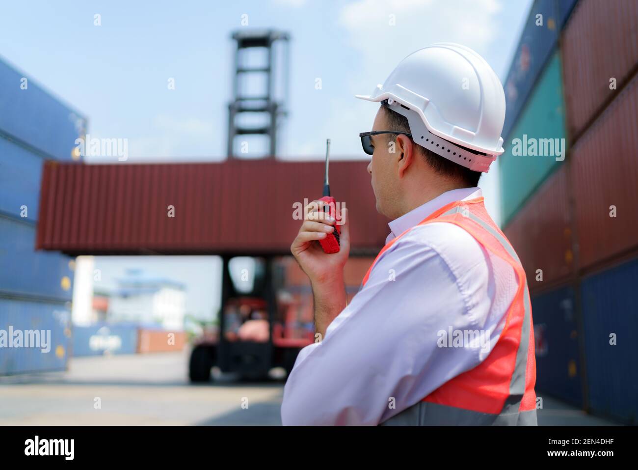Caucasian foreman man is using walkie talkie to command his workers ...