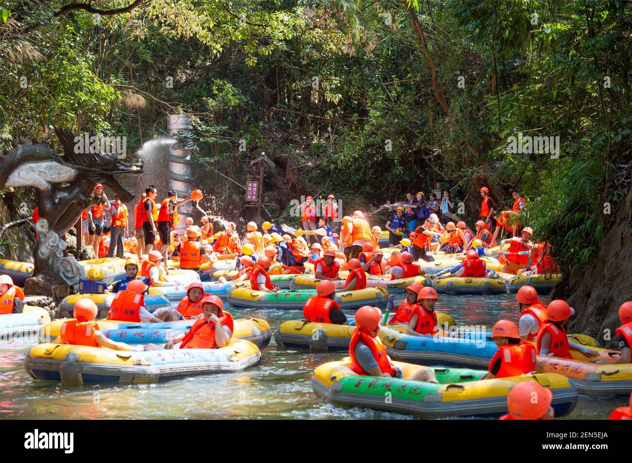A crowd of tourists sitting on inflatable rafts jam a stream as they ...
