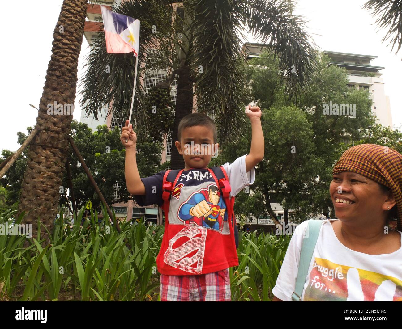 A young boy holds a Philippine flag, as his mother looks on during the ...