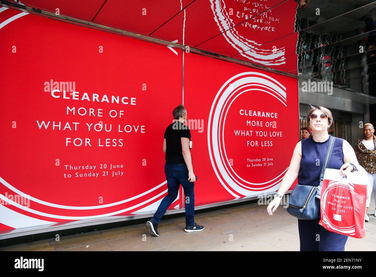Shoppers walk past a store window display on Oxford Street as summer ...