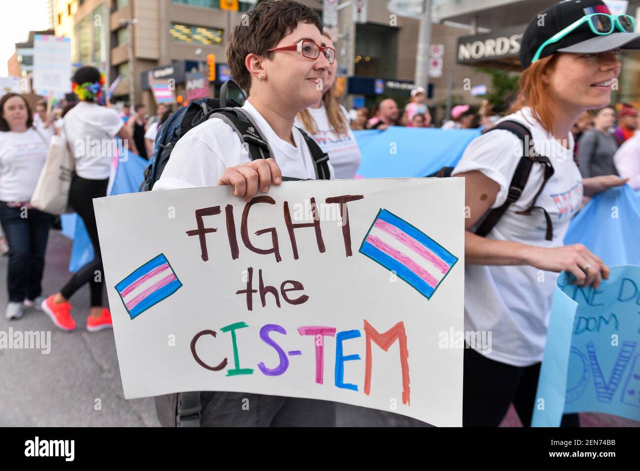 A protester holds a placard during the Trans march. Spectators ...