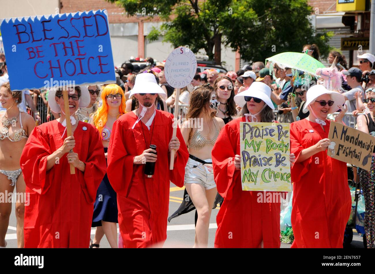 Parade participants dressed in red while holding placards during the ...