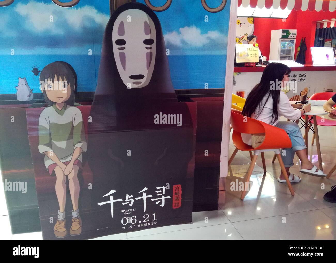 --FILE--A filmgoer waits in front of a poster of Japanese animated film ...